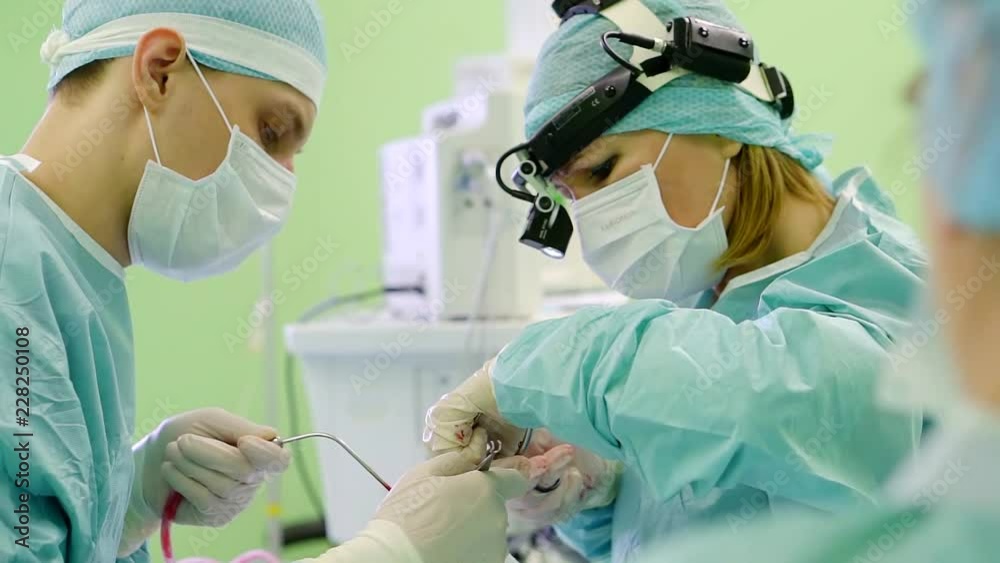 team of professional surgeons are working over nose of patient under ...