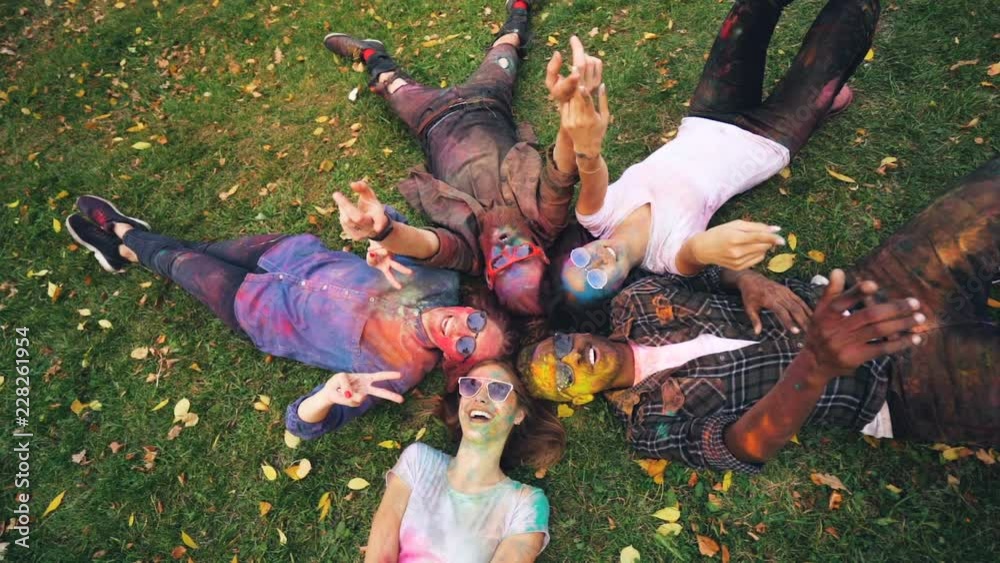 Slow motion portrait of relaxed people lying on grass in park with ...
