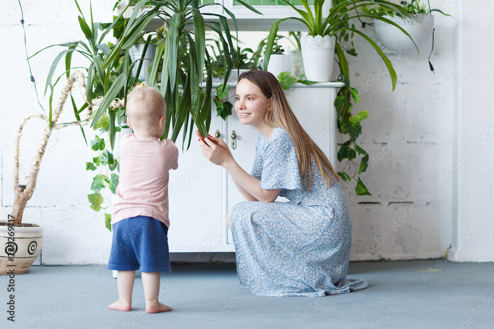 Young beautifull mom introduces child to plants in garden, mother ...