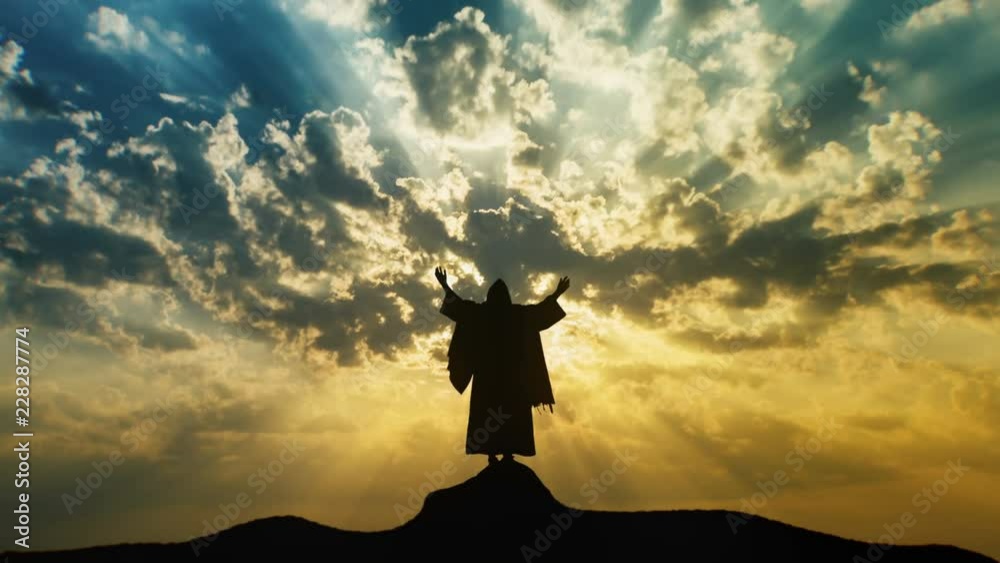 Silhouette of Jesus praying on hill crest with sun rays and mystic ...