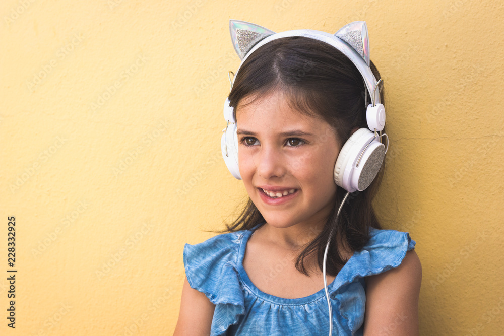 Smiling little girl sitting with cat ears design headphones on ...