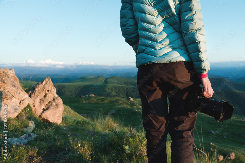 Photos on the shoulders behind the girl photographer in nature with a ...