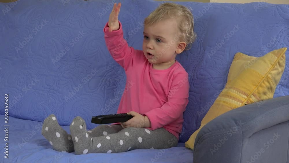 emotional female child with remote control in hands concentrated on ...