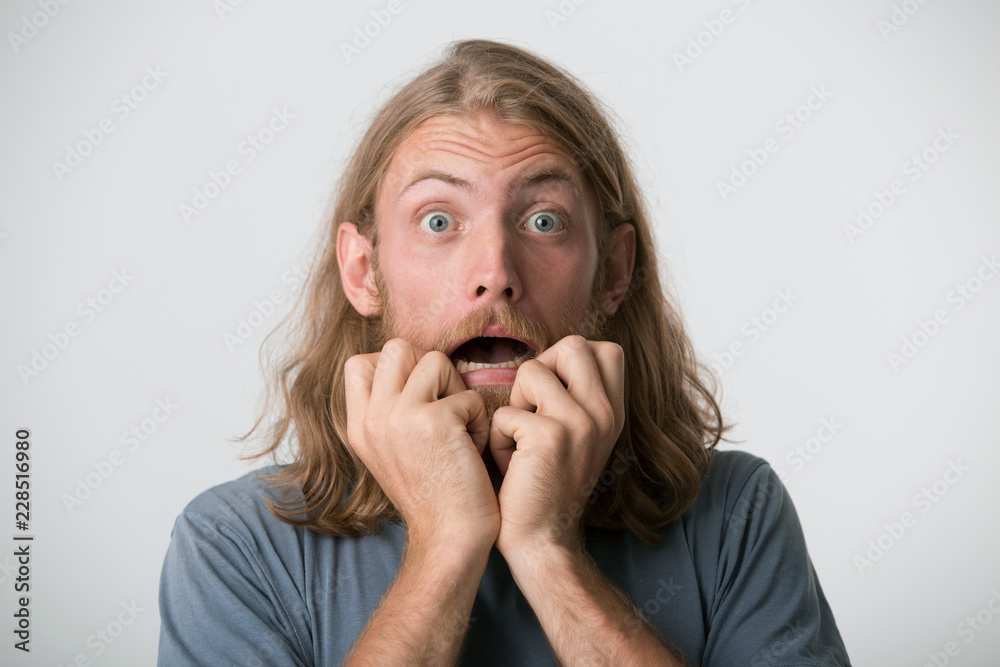 Stunned and shocked young guy with blond hair down to the shoulders and ...