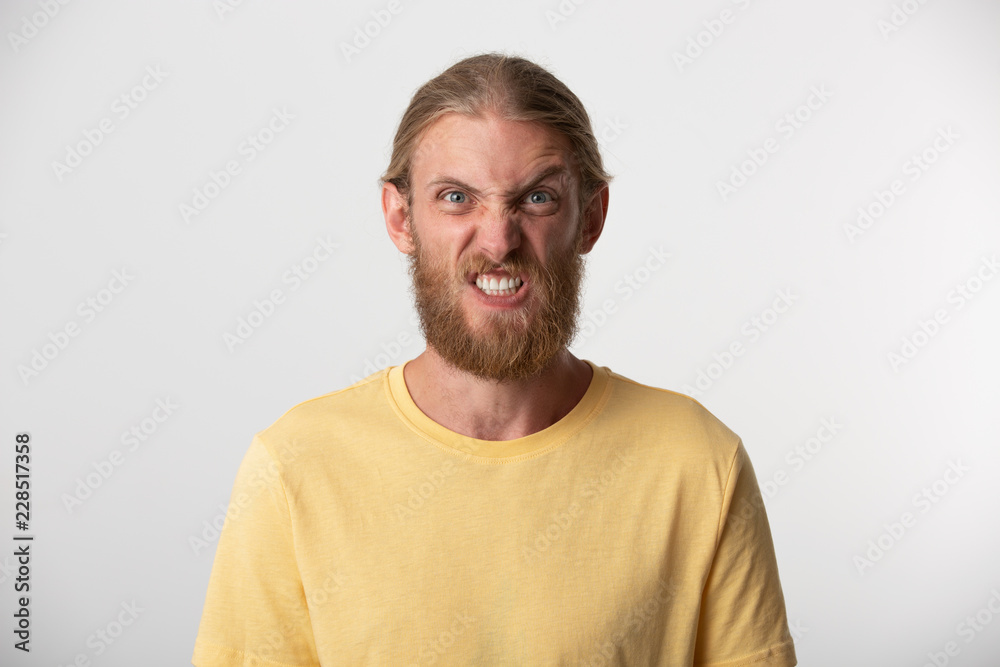 Young bearded guy with grin like an animal, making a face. Angry face ...