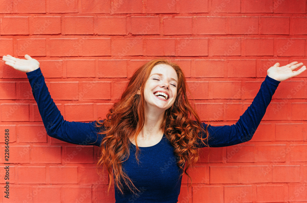 Woman shrugging while standing in front of wall Stock Photo | Adobe Stock