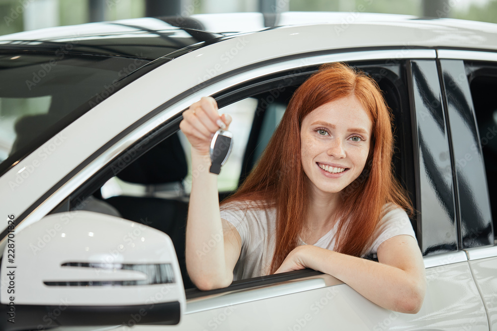 Caucasian happy ginger woman in red luxury auto smiling at camera and ...