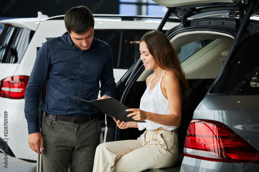 Making a decision. Beautiful young couple choosing a new car at the car ...