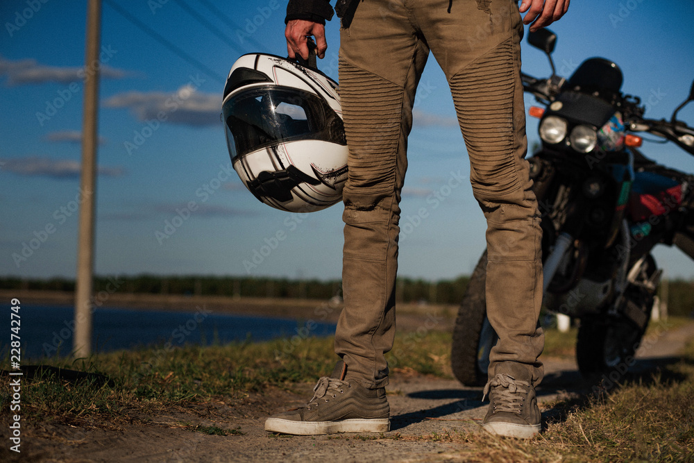 Legs of a biker near his vehicle. Close-up vies of motorcycler's legs ...