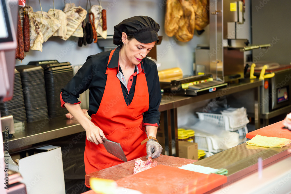 Female butcher cutting meat at counter in butchery Stock Photo | Adobe ...