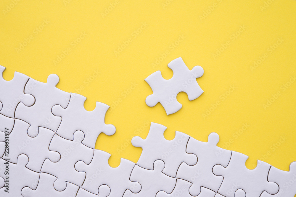 Unfinished white jigsaw puzzle on yellow background. Business strategy ...