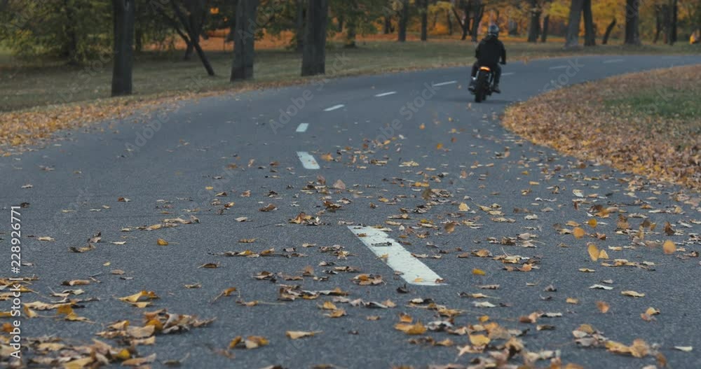 Motorcyclist man riding a motorcycle cafe racer on an empty road in ...