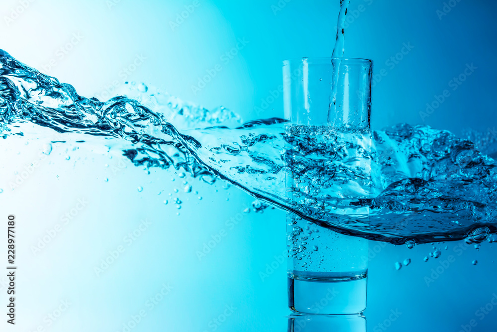 Blue water splash pours into a glass on a beautiful blue sea wave ...