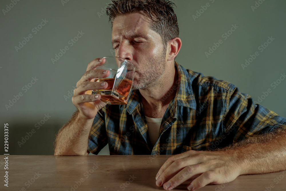 young attractive wasted and depressed addict and alcoholic man with whiskey glass thoughtful and ...
