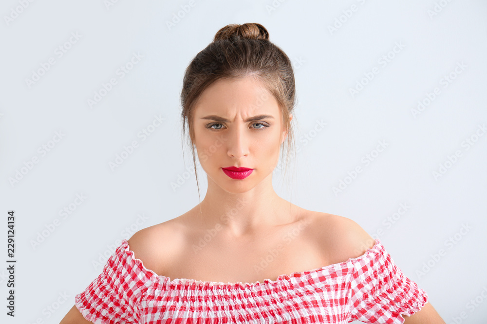 Frowning young woman on light background Stock Photo | Adobe Stock