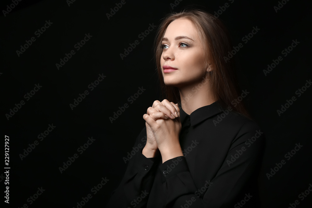 Beautiful young woman praying on dark background Stock Photo | Adobe Stock