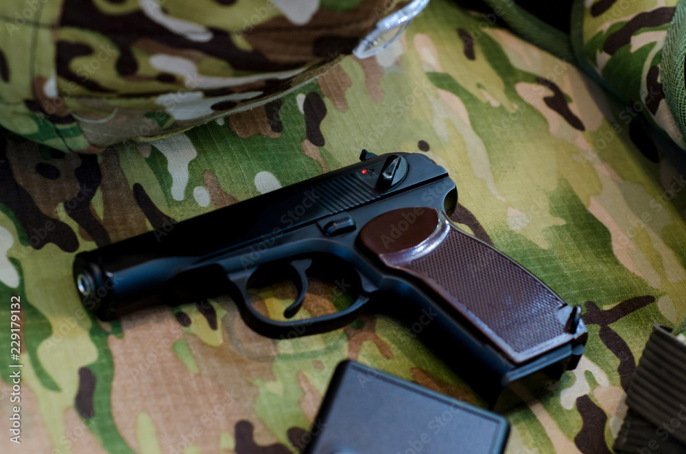 Black metal pistol gun with military equipment. Stock Photo | Adobe Stock