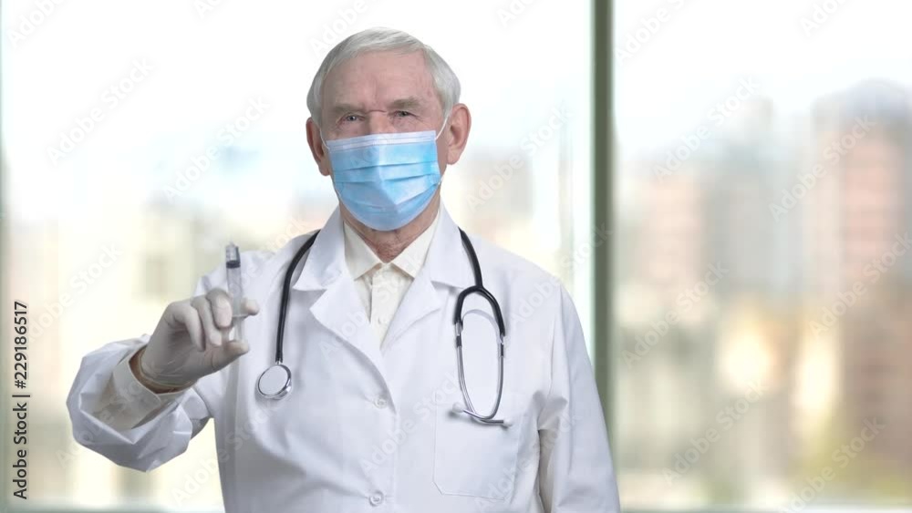 Press syringe in the air. Serious old doctor making shot medicine from ...