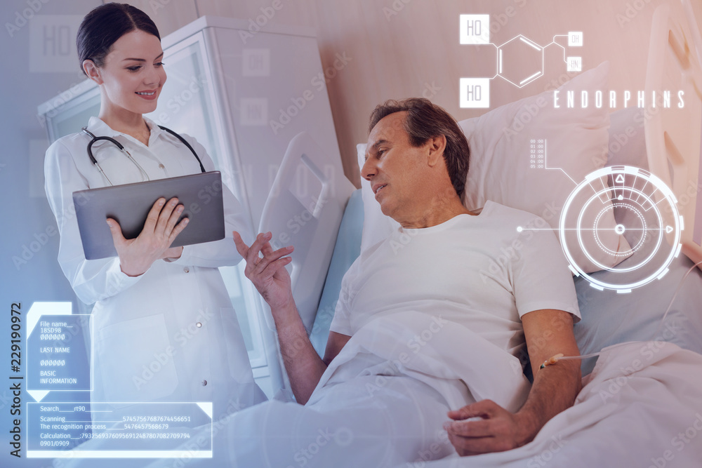 Asking questions. Calm experienced doctor holding a modern tablet and ...