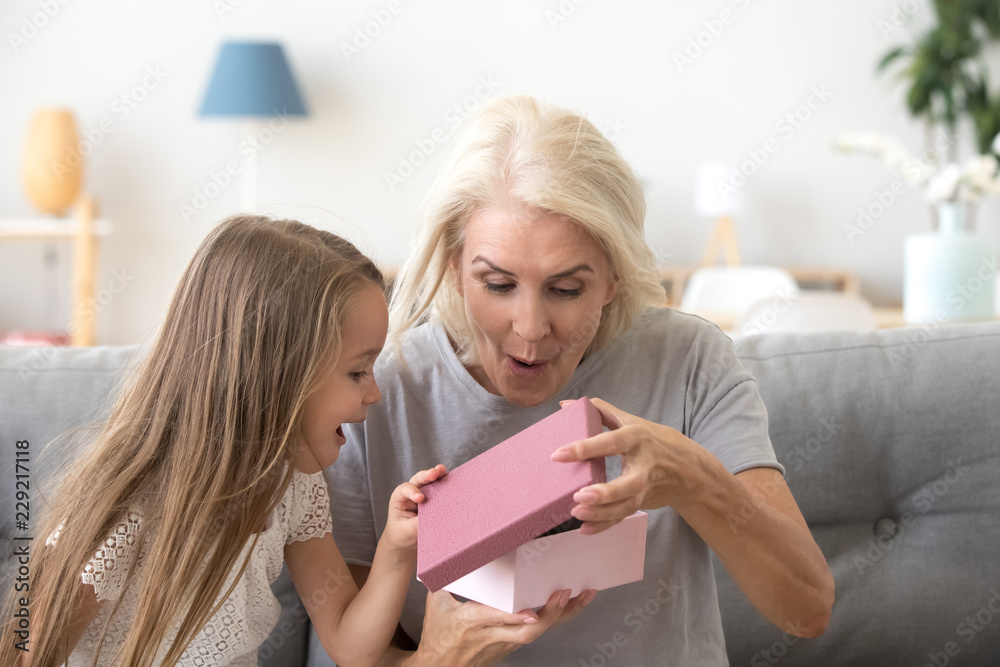 Excited granddaughter open birthday present together with granny, spend ...