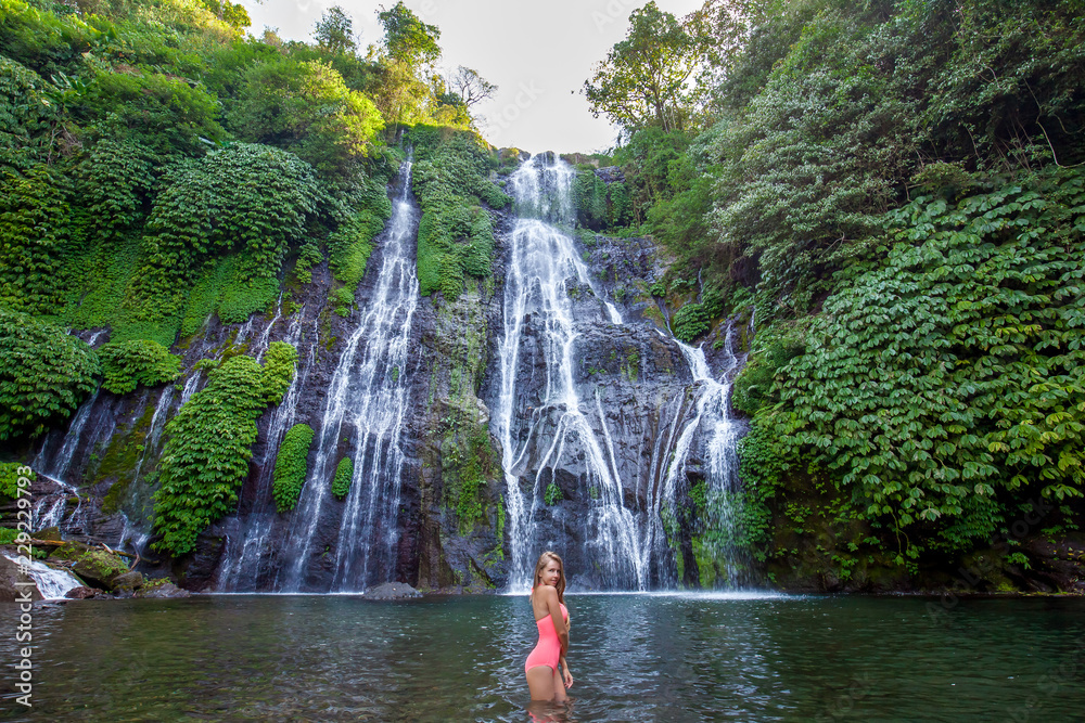 Young woman in swimsuit in front of Banyumala twin waterfalls on Bali ...