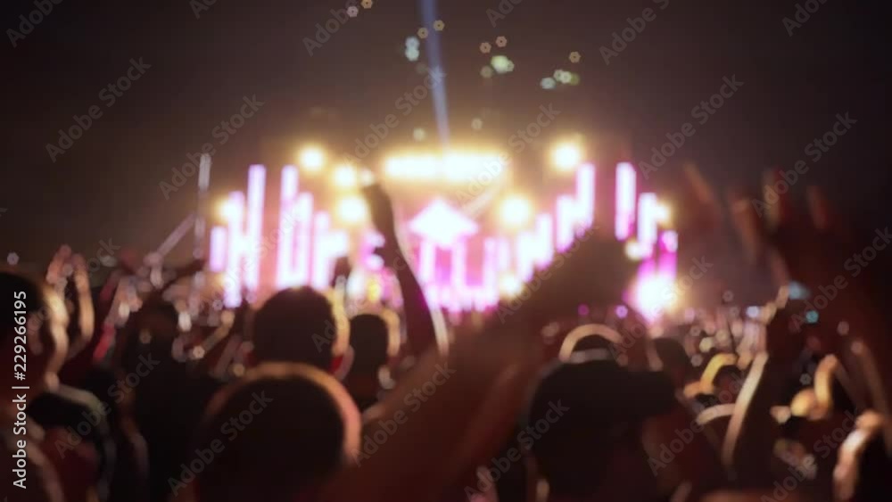 Happy people are watching an amazing musical concert. Merry fans jump ...