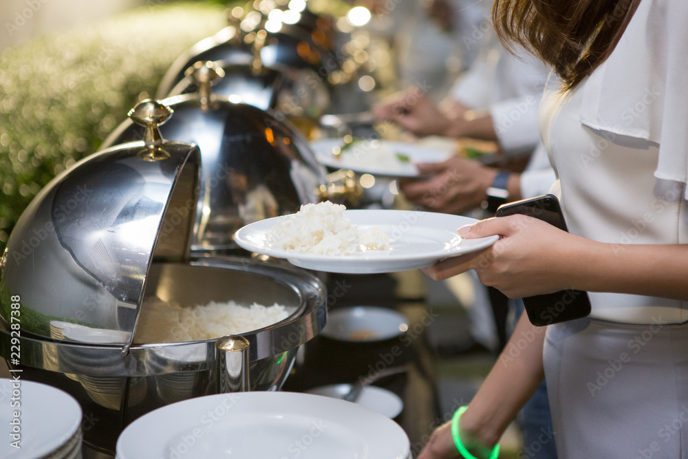Women are scooping food from chafing dishes Stock-Foto | Adobe Stock
