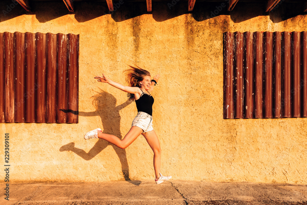 Happy teen jumping over an orange wall Stock Photo | Adobe Stock