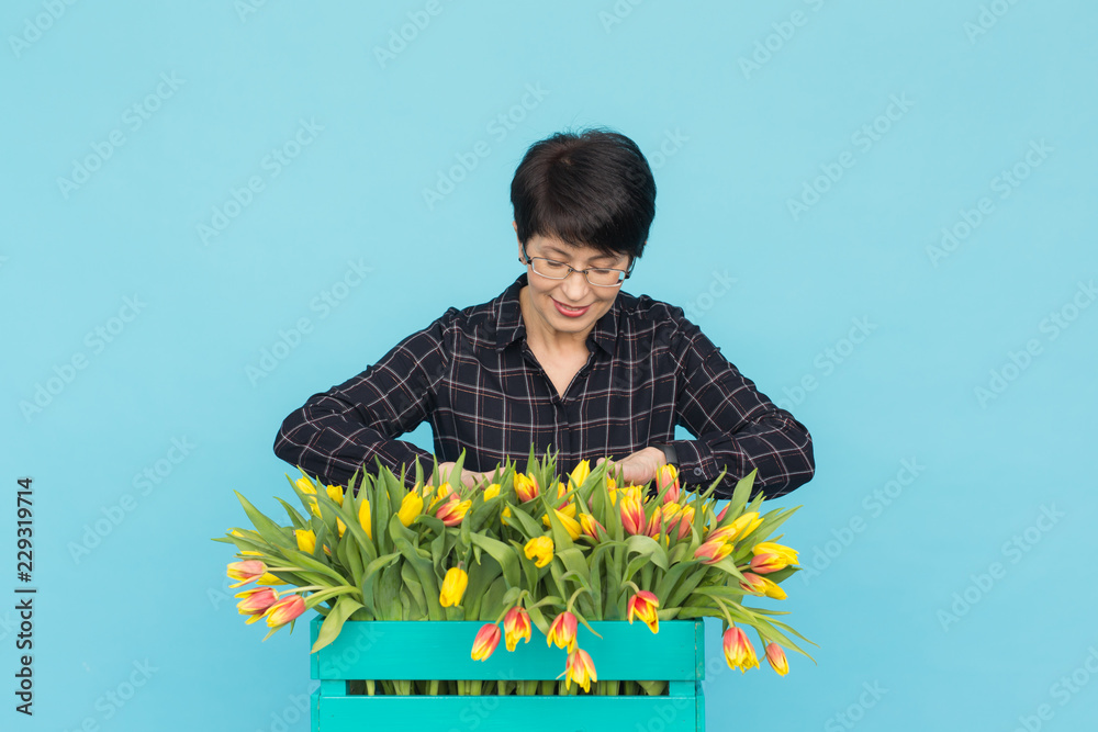 Charming brunette female florist sorts out tulips in the box, selects ...