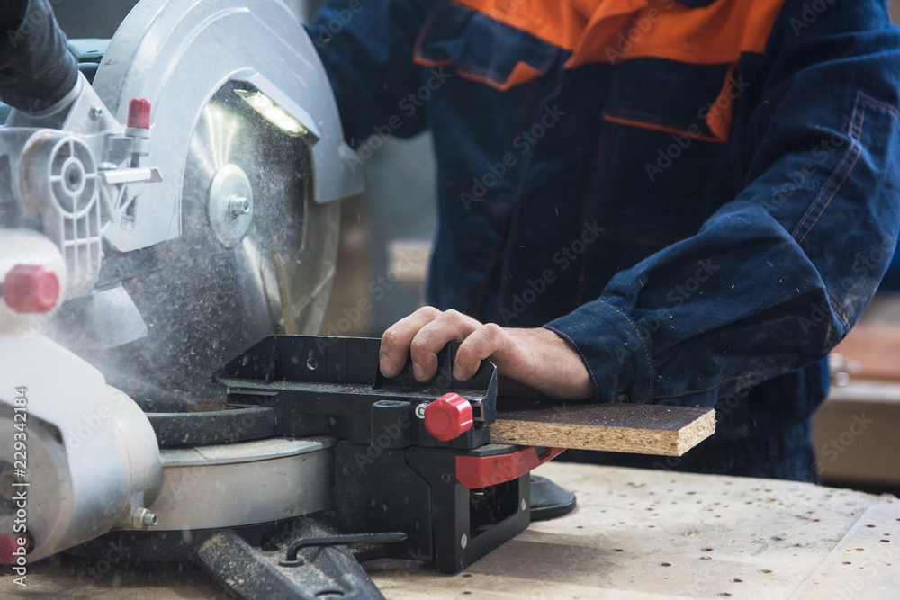 Furniture production or craft concept: worker sawing the wood surface ...