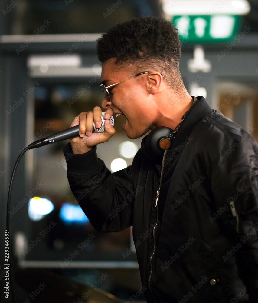 Black rapper performing with microphone. Side profile. Headphones ...