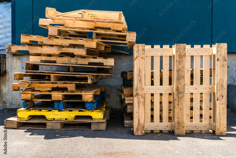 Pile of old wood pallet, dirty ground and blue exterior wall, used for ...