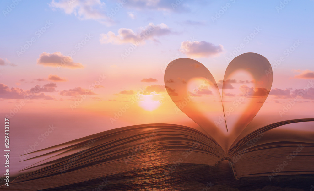 Heart shape from book against peaceful sunset. Reading, religion, love ...