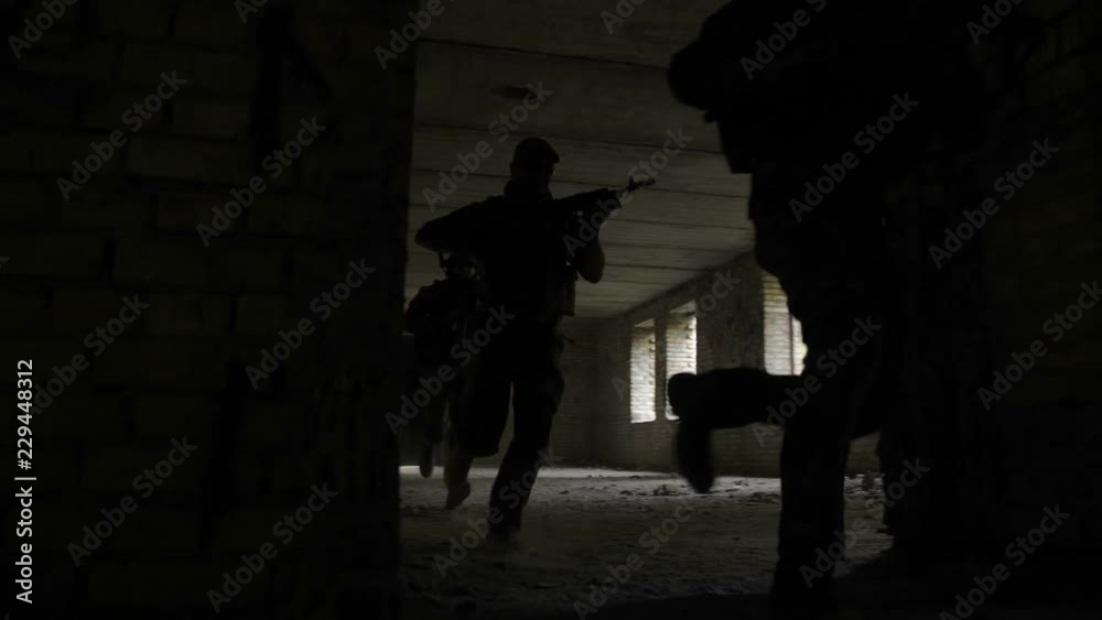 Squad of fully equipped and armed soldiers running through abandoned ...