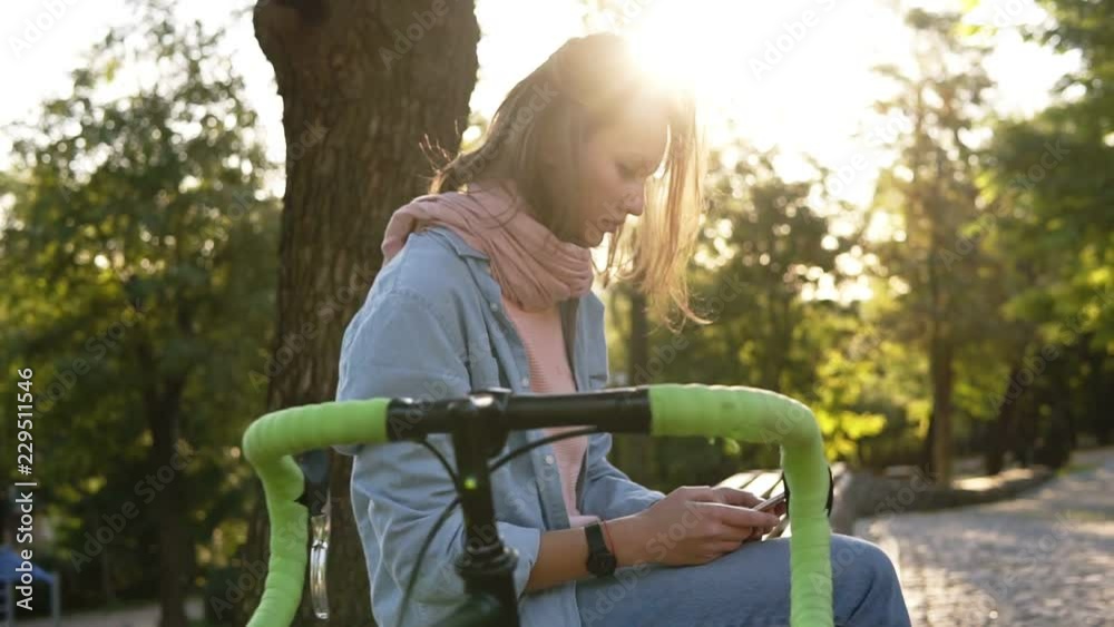 Thoughtful girl sitting on the bench in the city park with her trekking ...