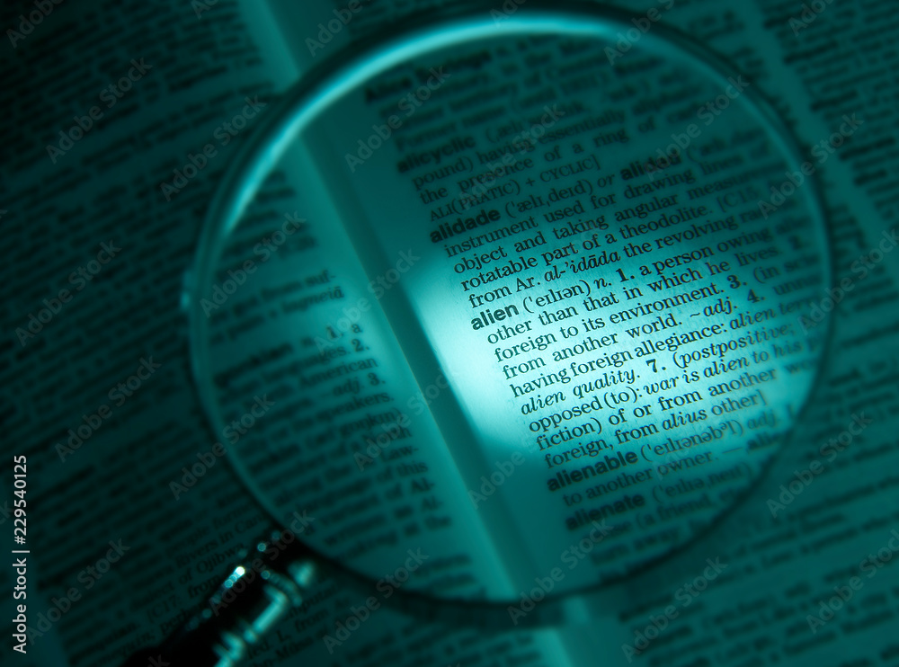 MAGNIFYING GLASS ON DICTIONARY PAGE SHOWING DEFINITION OF THE WORD ...