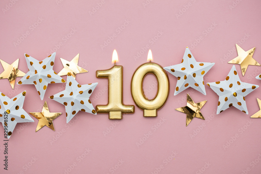 Number 10 gold candle and stars on a pastel pink background Stock Photo ...
