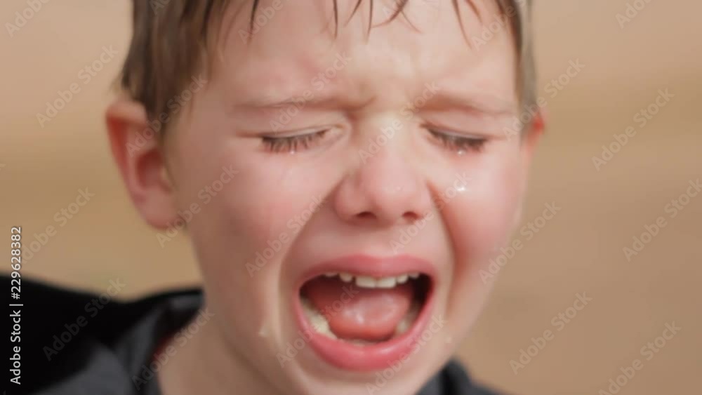 A young boy cries inconsolably on a rainy, windy day. Eyes remain ...