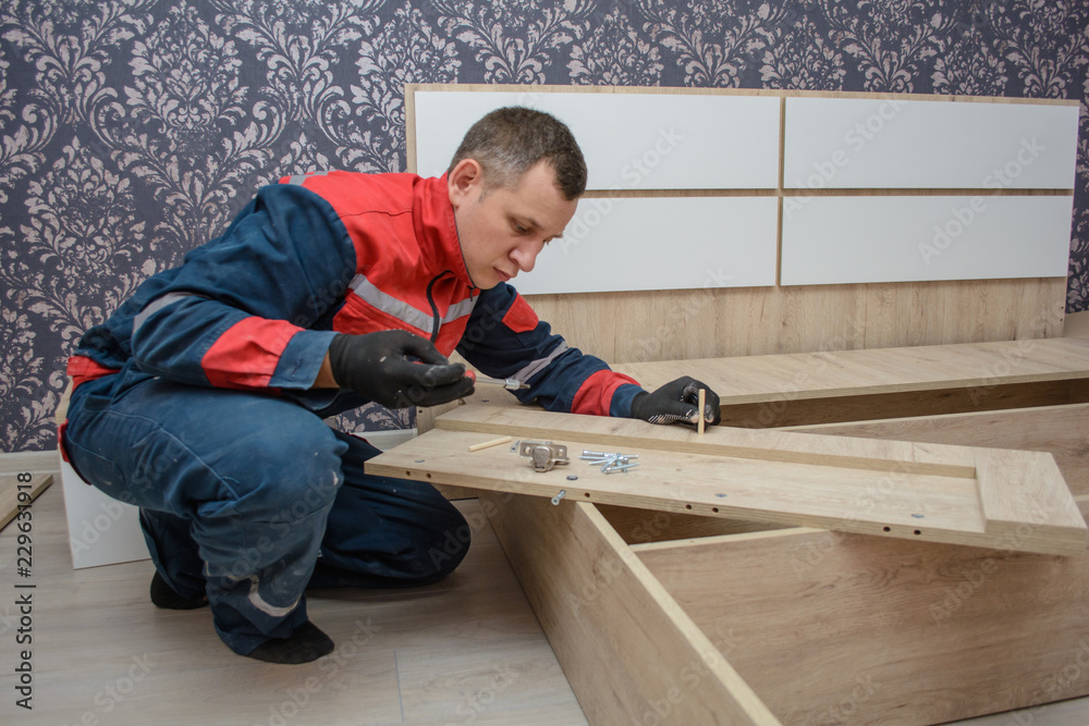 Assembling new wooden bed by hand in room. Man putting together new ...