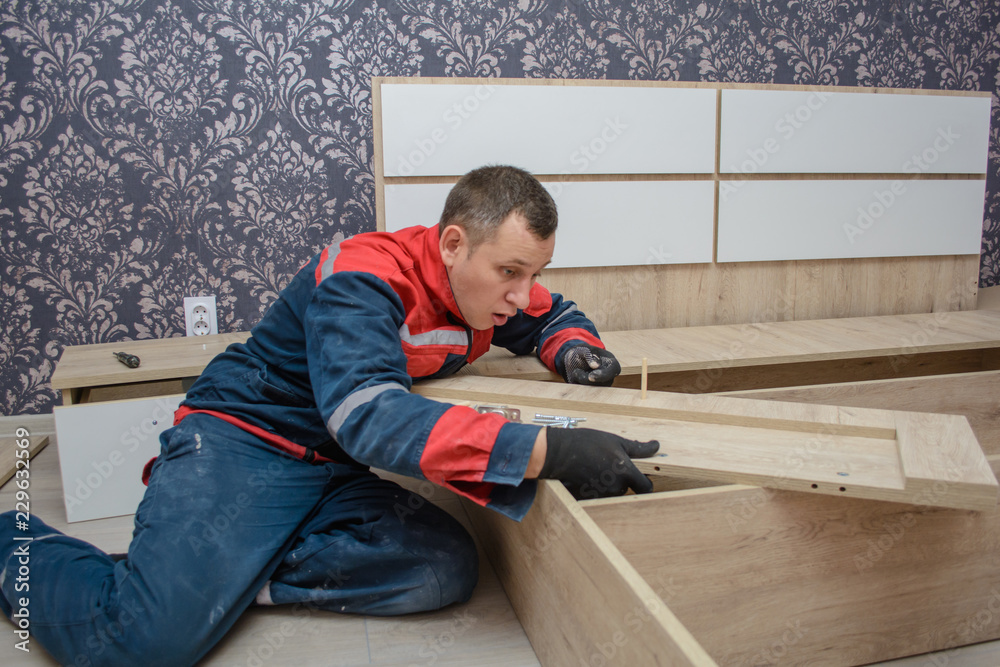Assembling new wooden bed by hand in room. Man putting together new ...