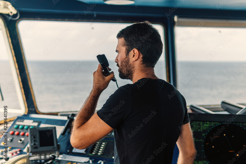 Marine navigational officer is reporting by VHF radio during navigation ...