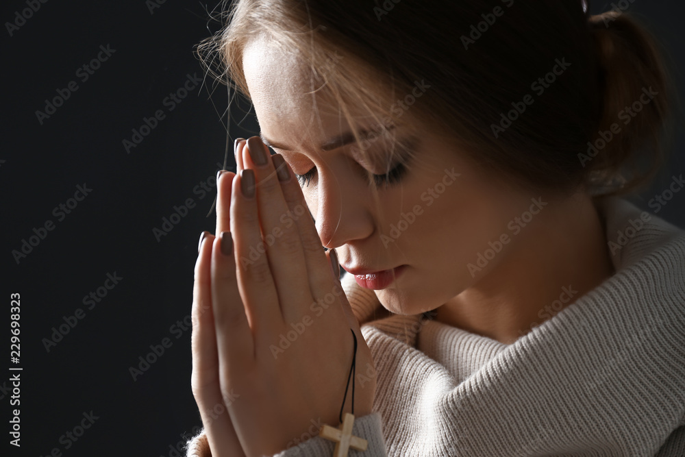 Beautiful young woman praying on dark background Stock Photo | Adobe Stock