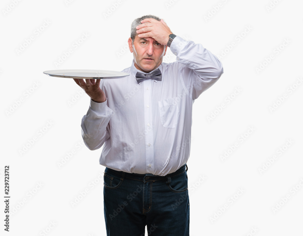 Handsome senior waiter man holding silver tray over isolated background ...