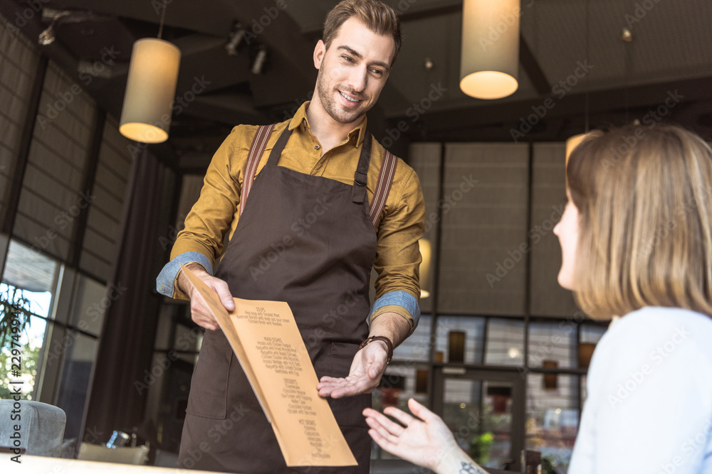 happy young waiter showing menu list to female customer in cafe Stock ...