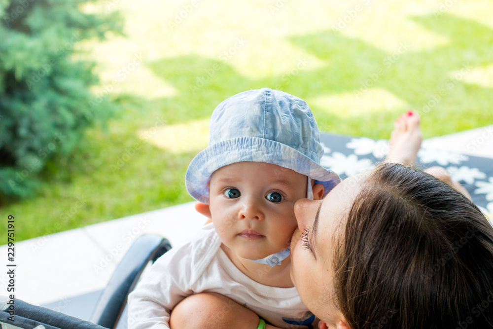 Cheerful mother hugging, cuddling and cheek kissing child outdoor ...
