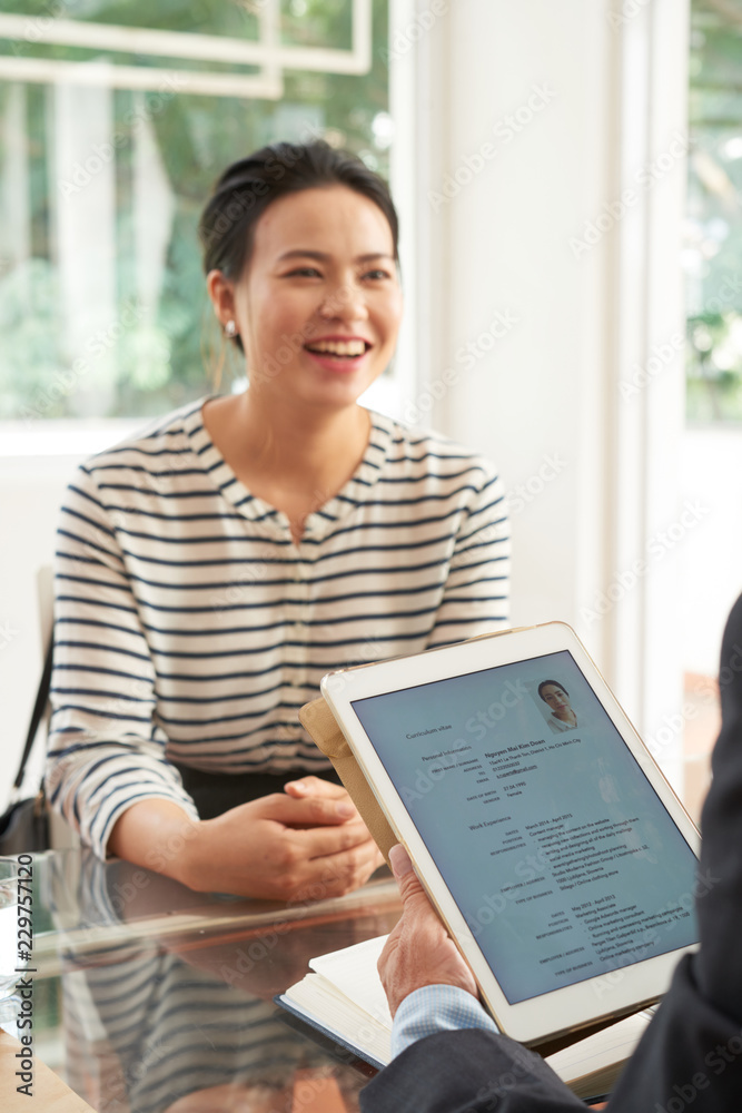 Female employee smiling during job interview, manager examining her ...
