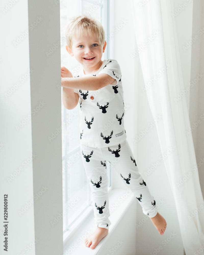 Smiling boy standing on a window sill Stock Photo | Adobe Stock