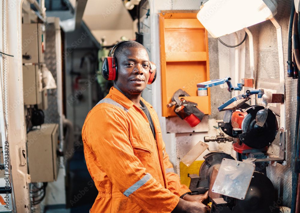 African marine engineer officer in engine control room ECR. He works in ...