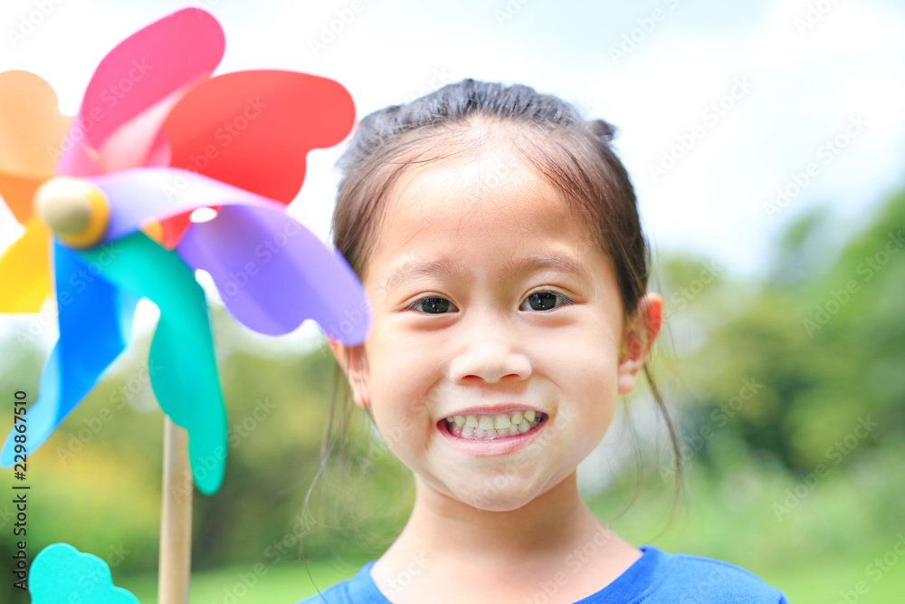 Close up cute little Asian child girl with wind turbine in the garden ...