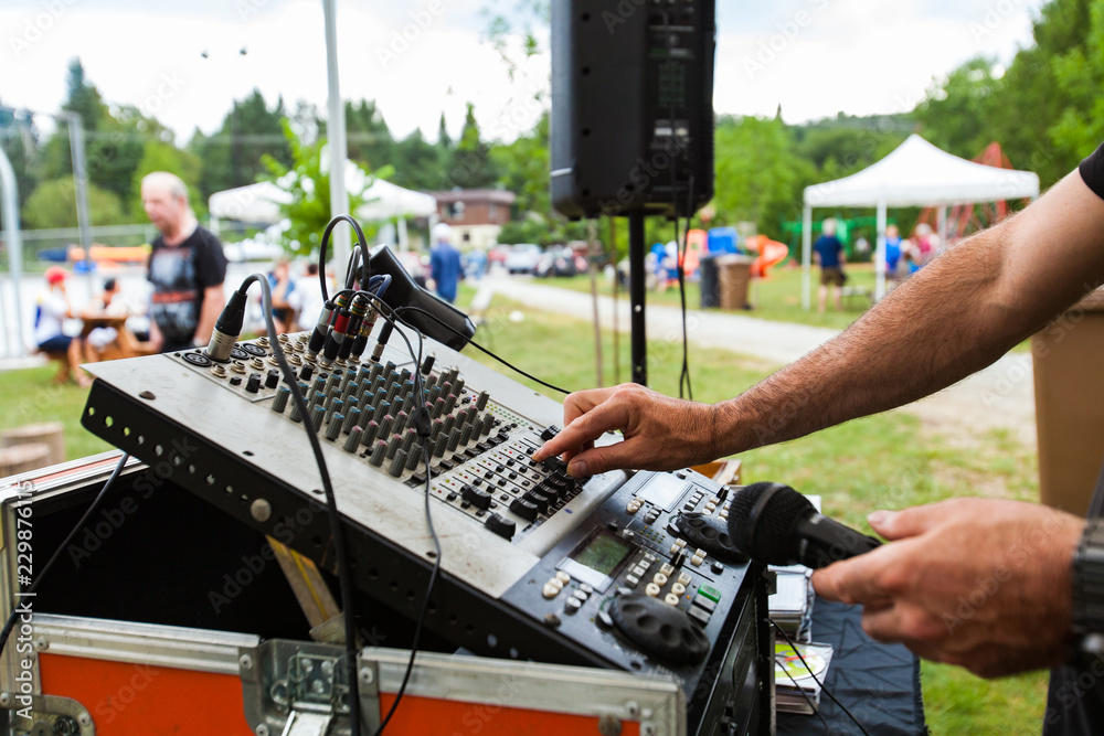 DJ is adjusting the levels on his mixing board during a community event ...